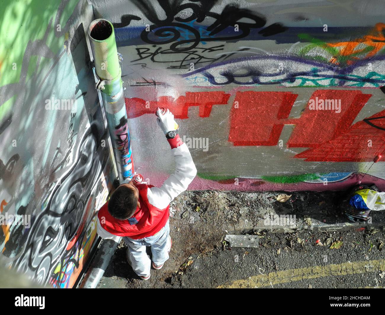 A birds-eye view young man spray-painting graffiti in Leake Street ...