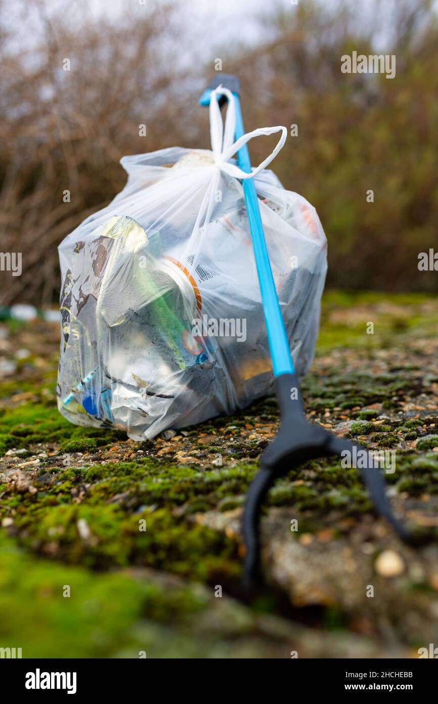 A litter picker and a full bag of rubbish that has been collected from ...