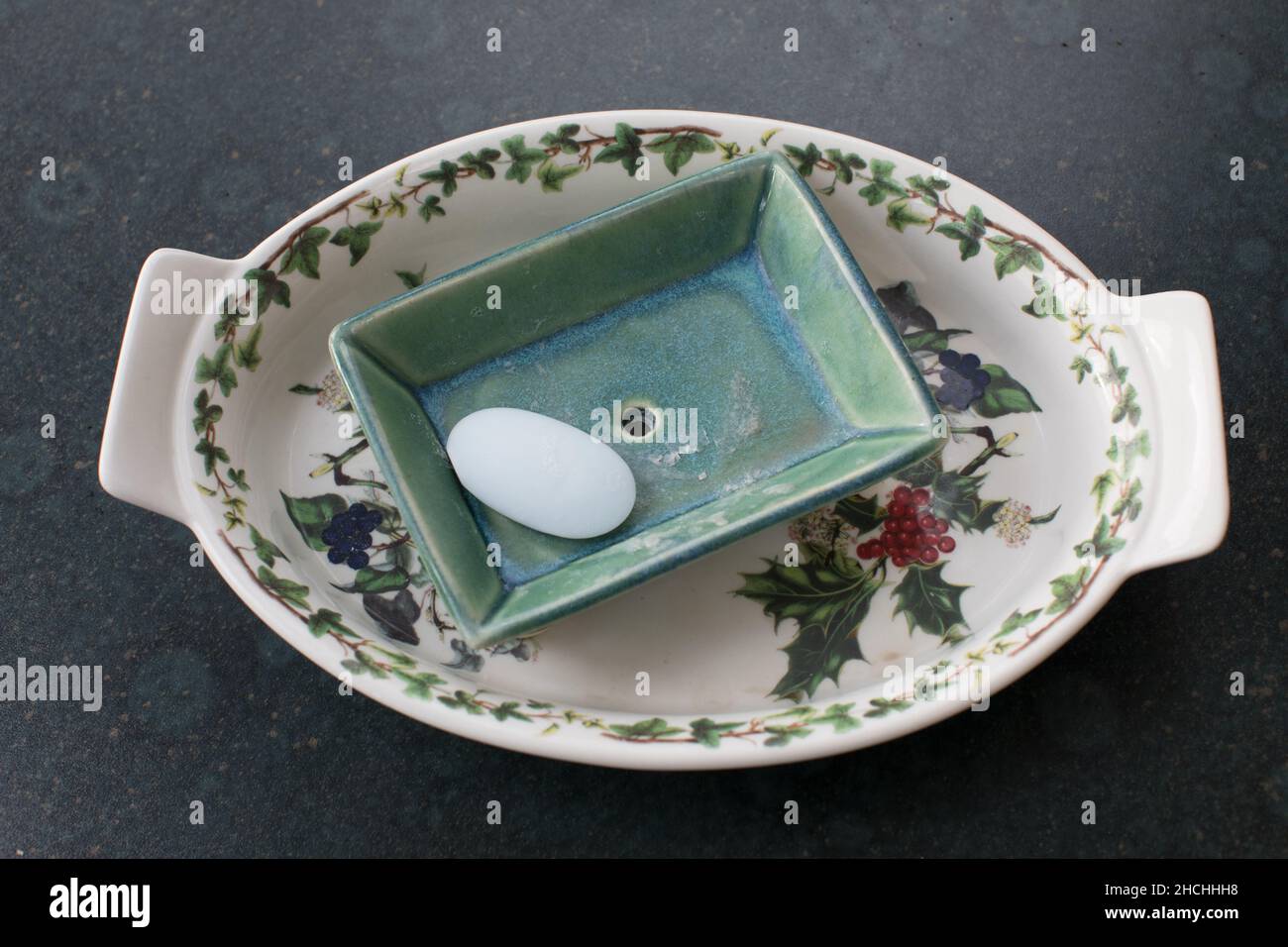Small amount of blue soap in a ceramic soap dish sitting in larger dish ...