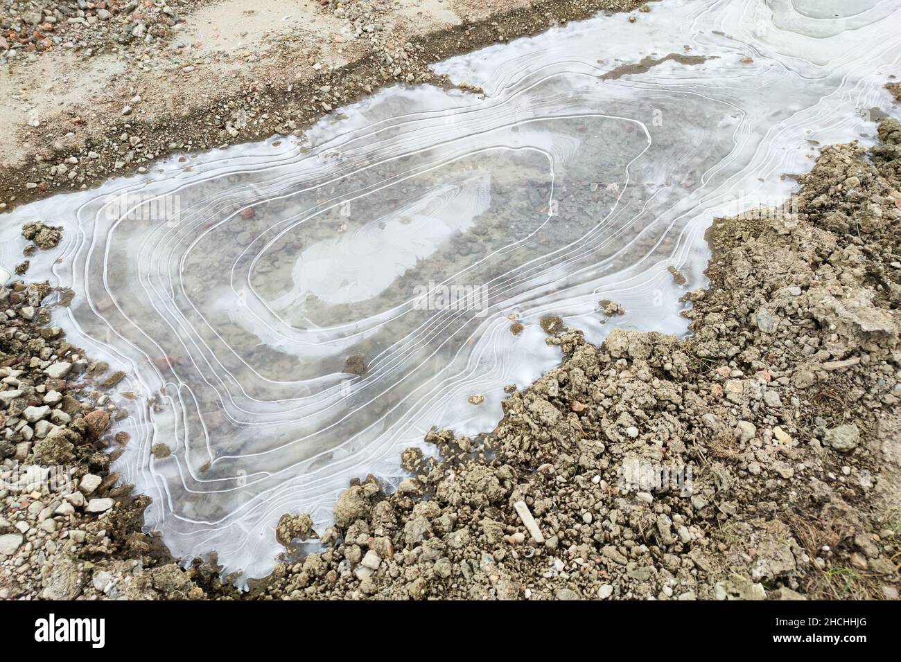 Oval shaped rings in the ice of a frozen puddle. Physical phenomenon ...