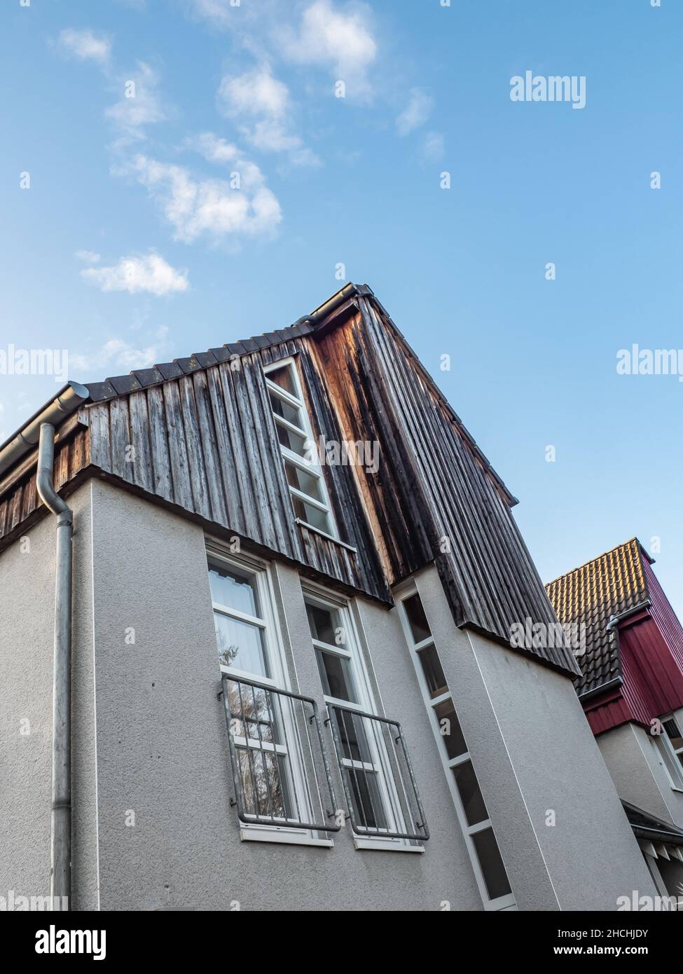 Vertical low angle shot of an modern wooden house against a blue sky ...