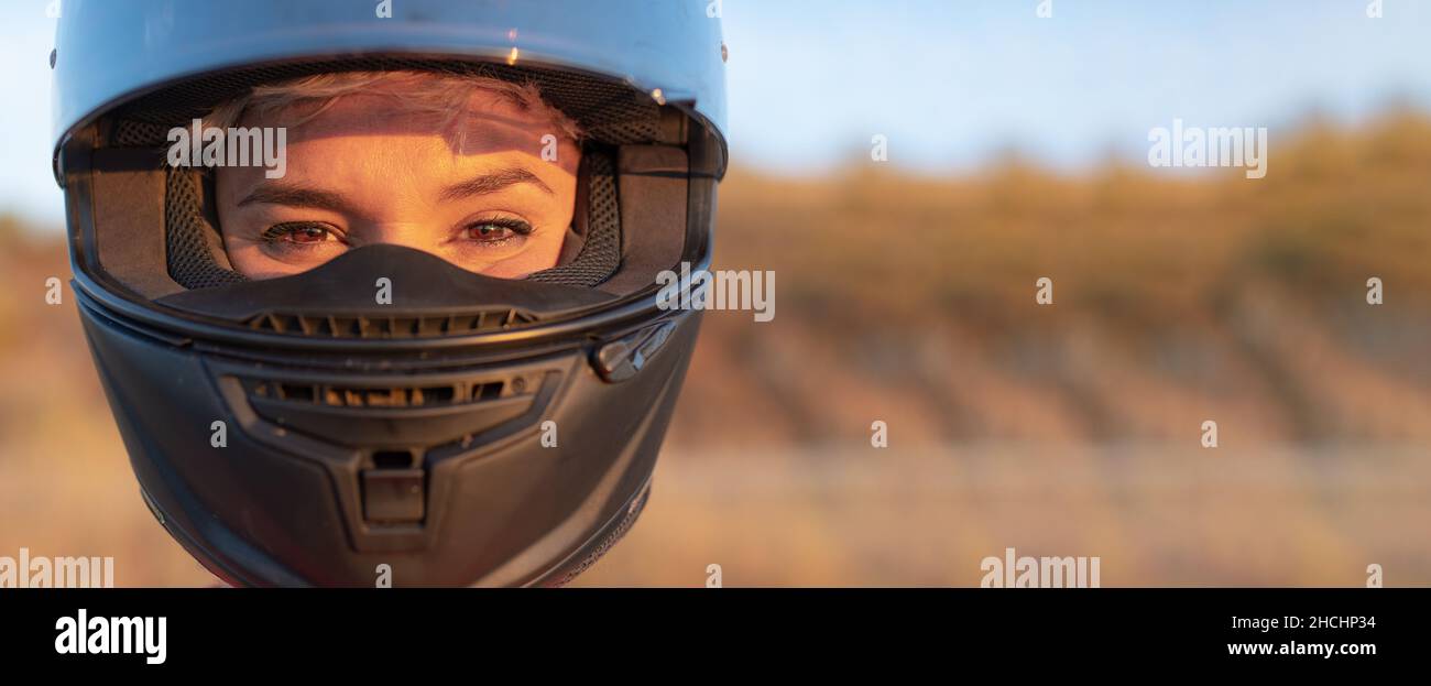 portrait of a young pretty blonde biker woman looking at camera with ...