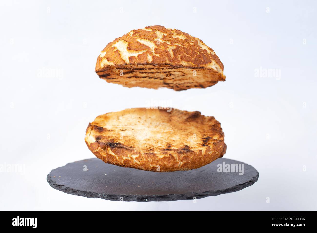 empty burger bun, levitating over a black stone tile, isolated on white ...