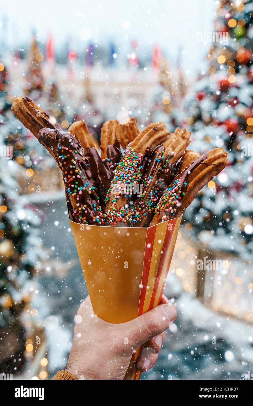 Churros waffles in a hand on the winter snow market. Churros Mexican ...