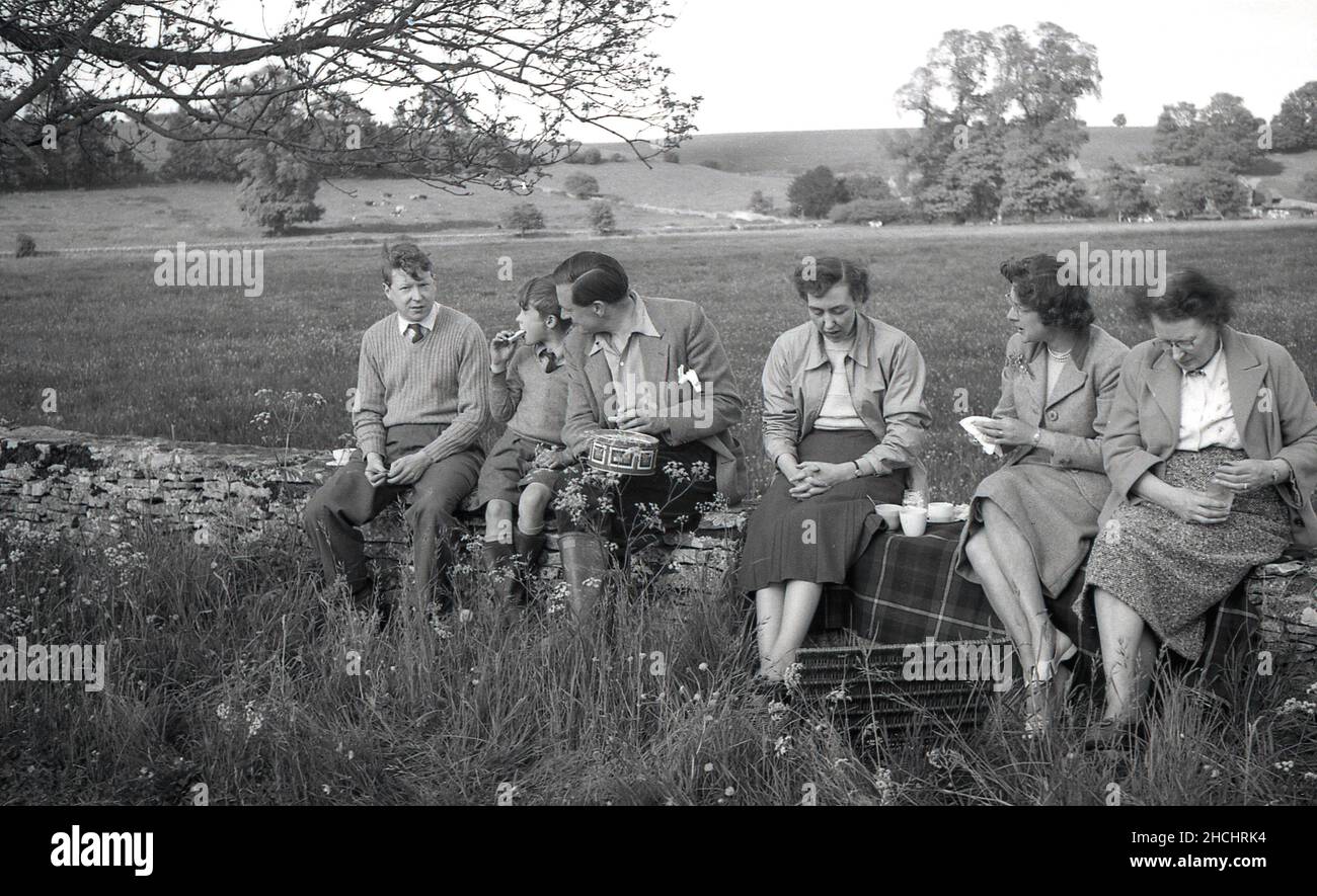 1950s, historical, outside in a country field, a farming family sitting ...