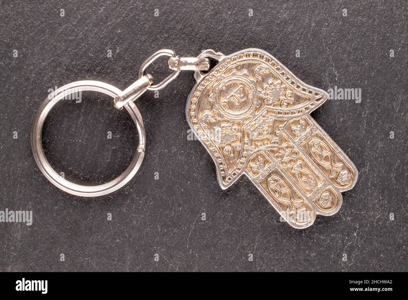 One metal keychain, the Jewish "hand of Miriam" on a slate stone, close ...