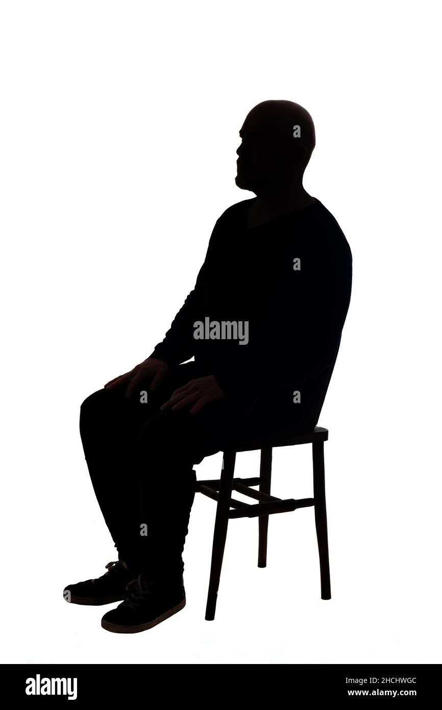 side view of silhouette of a man sitting on chair with casual clothes ...