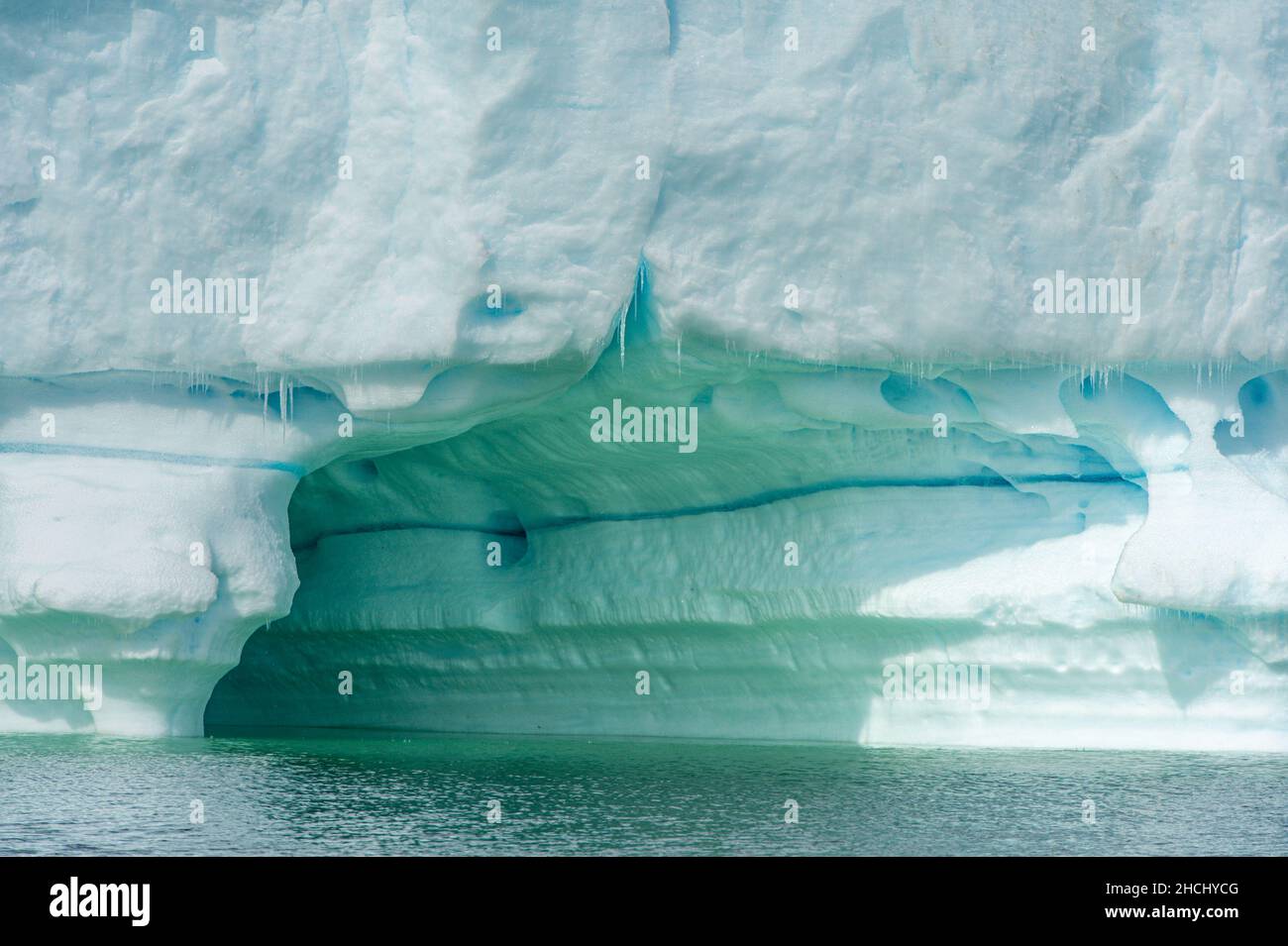An iceberg with a cave like opening and hanging icicles showing blue ...