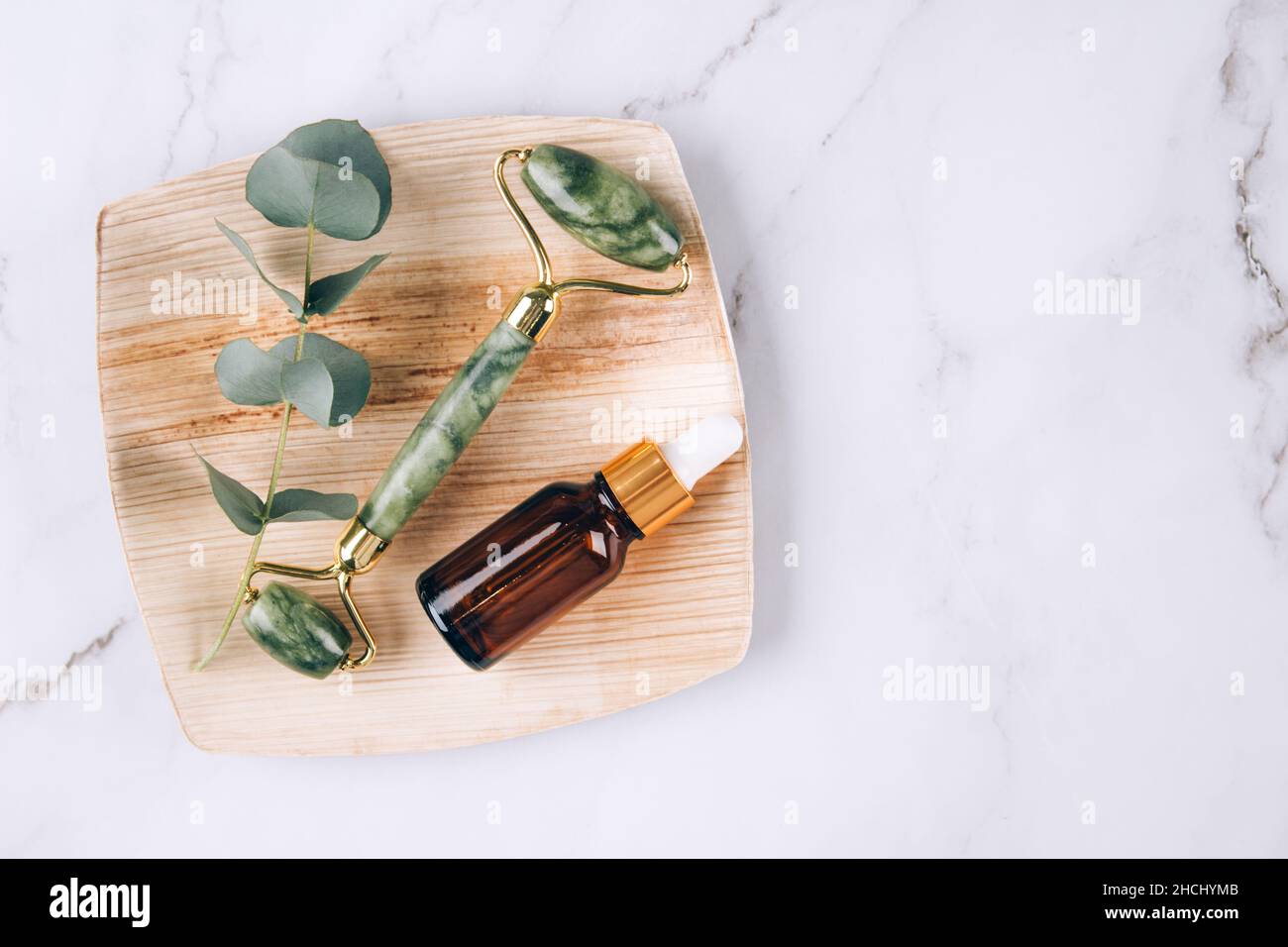 Flat lay composition with jade gua sha facial roller with beauty serum ...