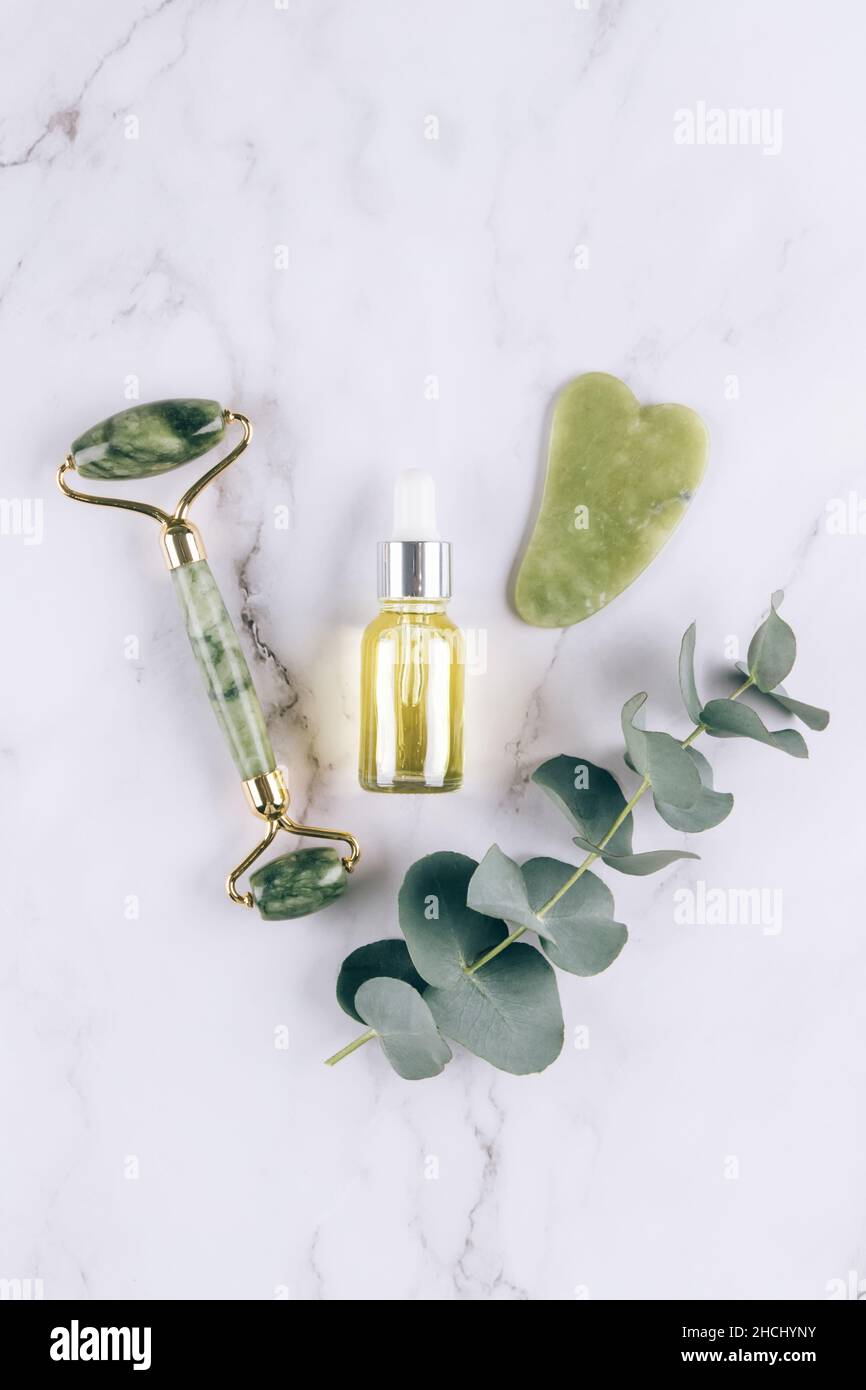 Vertical flat lay composition with jade gua sha facial roller with face ...