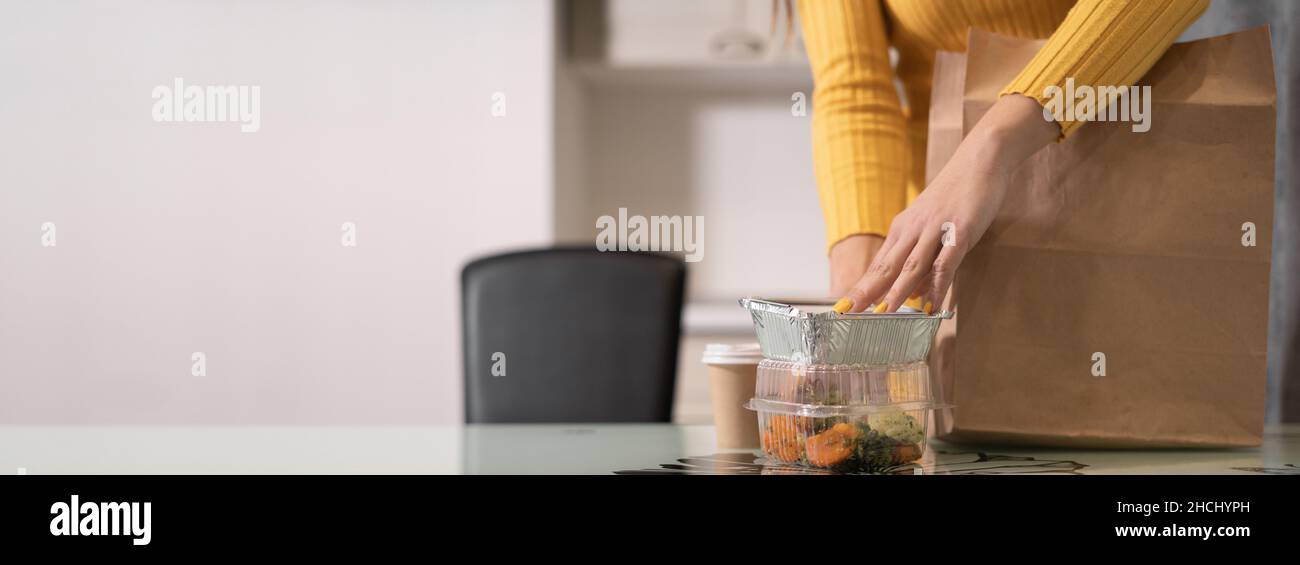 Close-up of female hands take out food in disposable trays from a paper ...