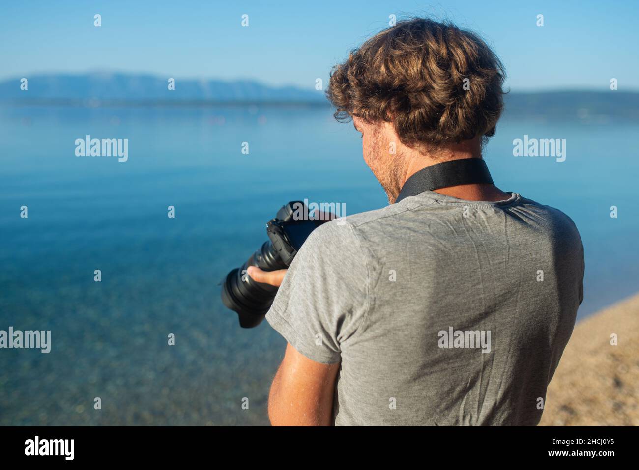 Rear view of a male photographer checking and setting his camera ...