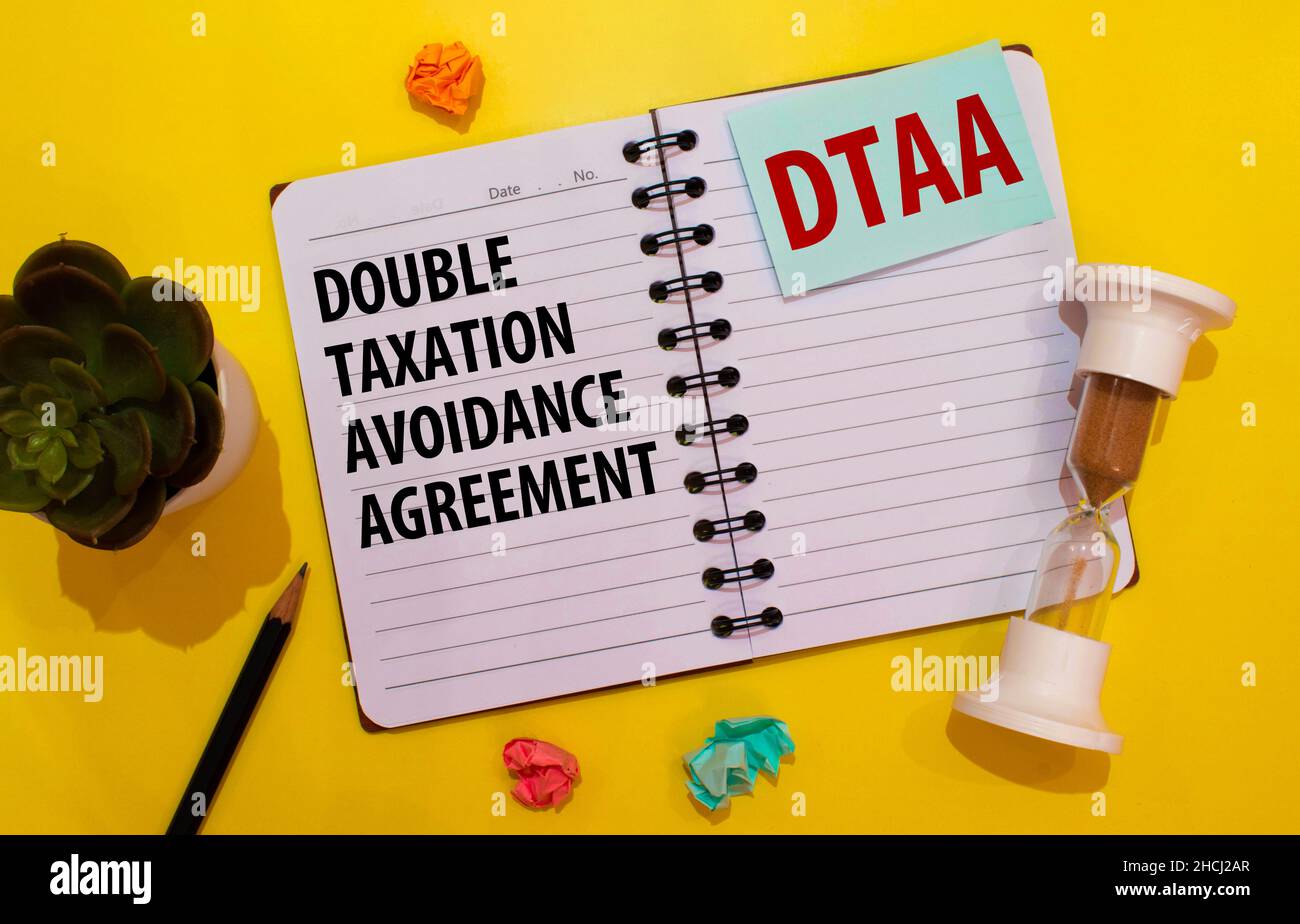 Closeup on businessman holding card with DTAA DOUBLE TAXATION AVOIDANCE ...