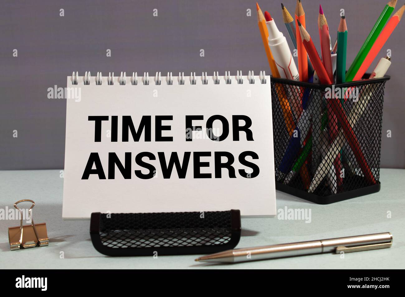On a pink background, pen and notebook with the text TIME FOR ANSWERS ...