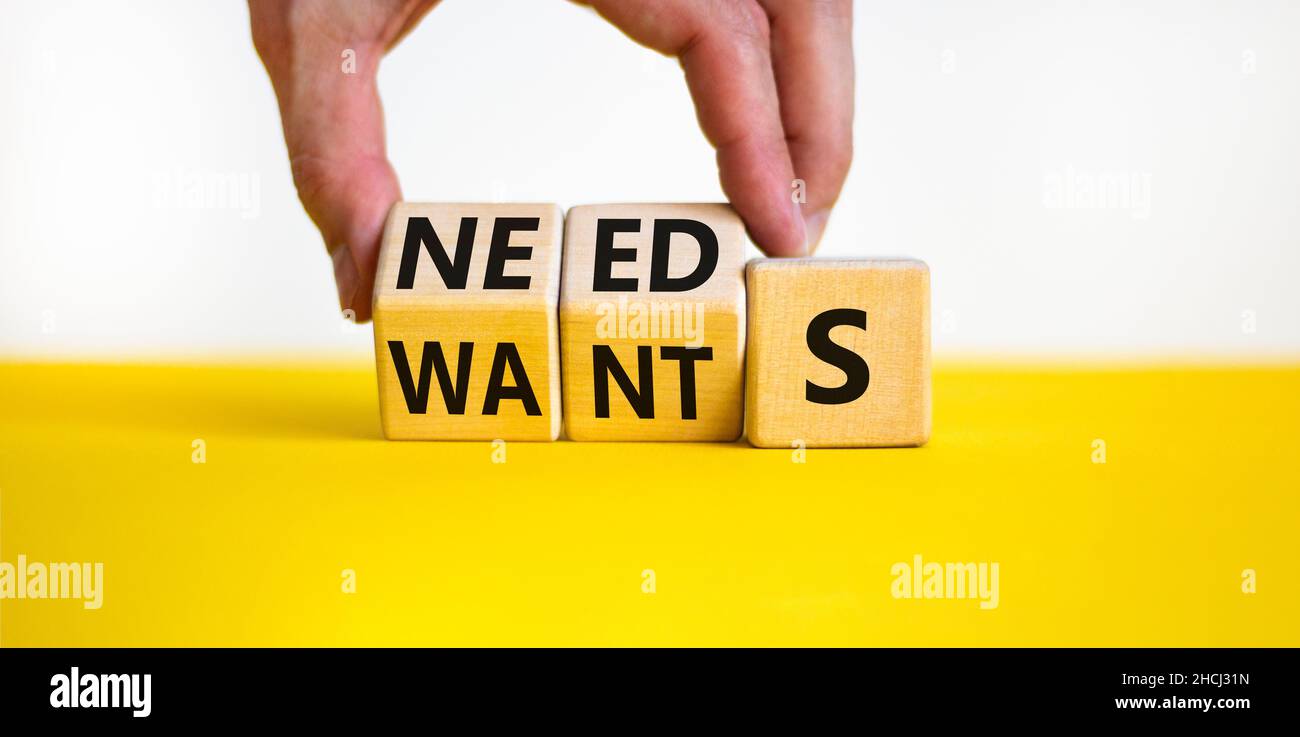 Wants or needs symbol. Businessman turns wooden cubes and changes the ...