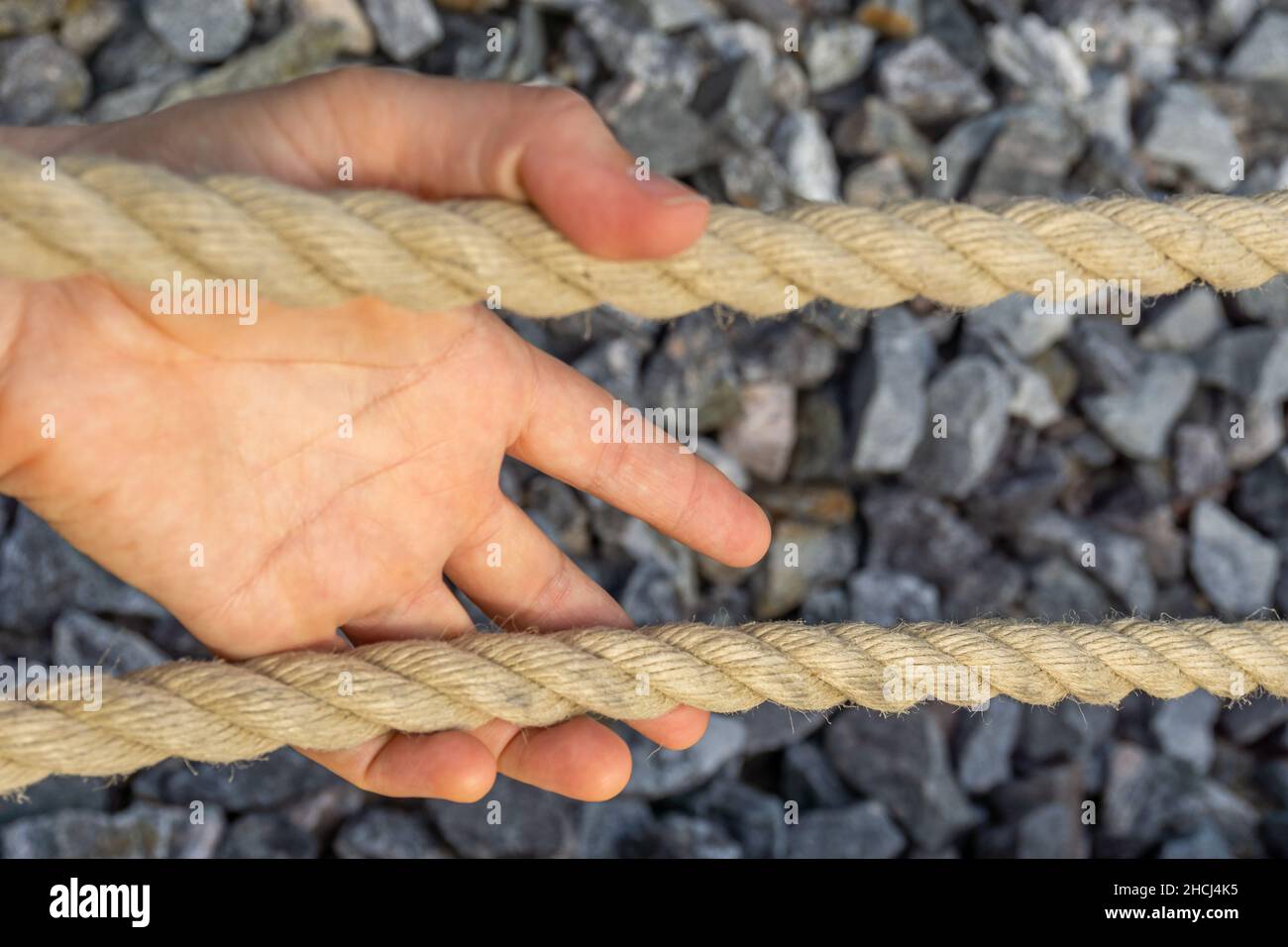 Sodertalje, Sweden - May 11, 2021: A hand holding two ropes with grey ...
