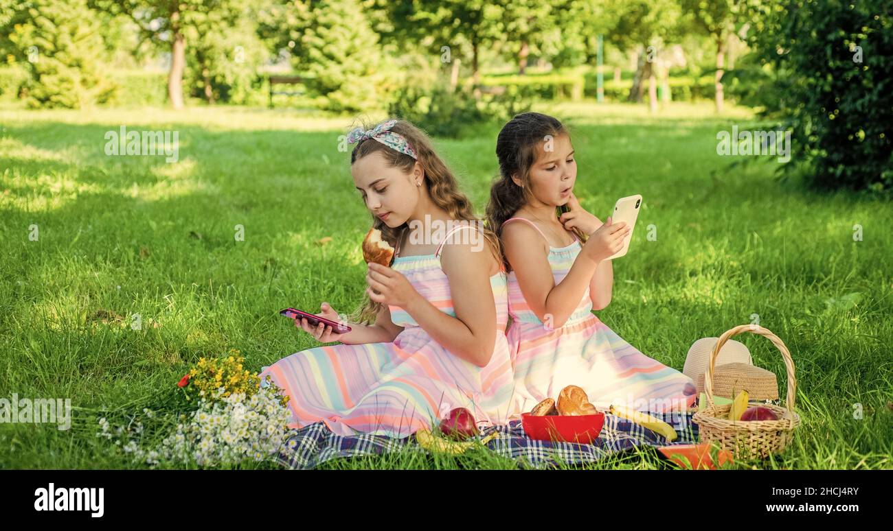 Little kids look at mobile phones suffering smartphone addiction at family summer picnic ...