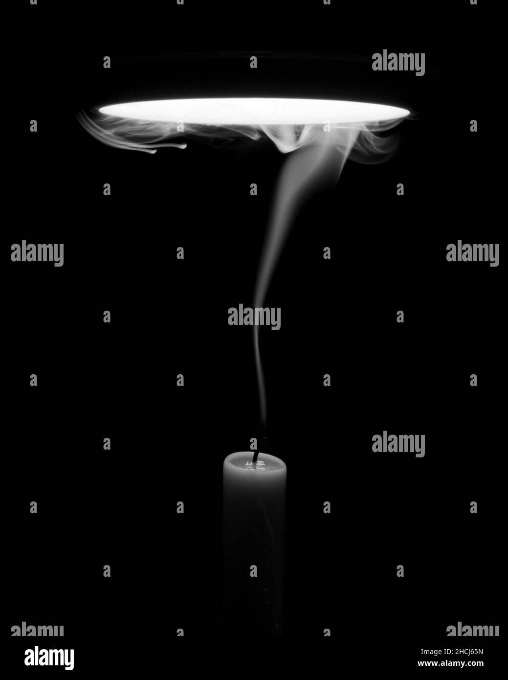 Grayscale of an extinguished candle with white smoke in the dark under ...