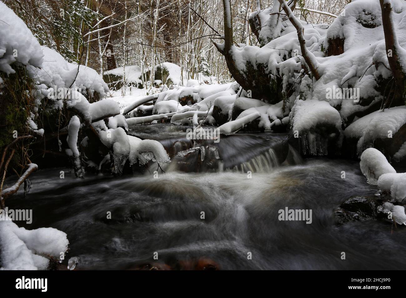River water flowing through the stones covered with a layer of snow in ...