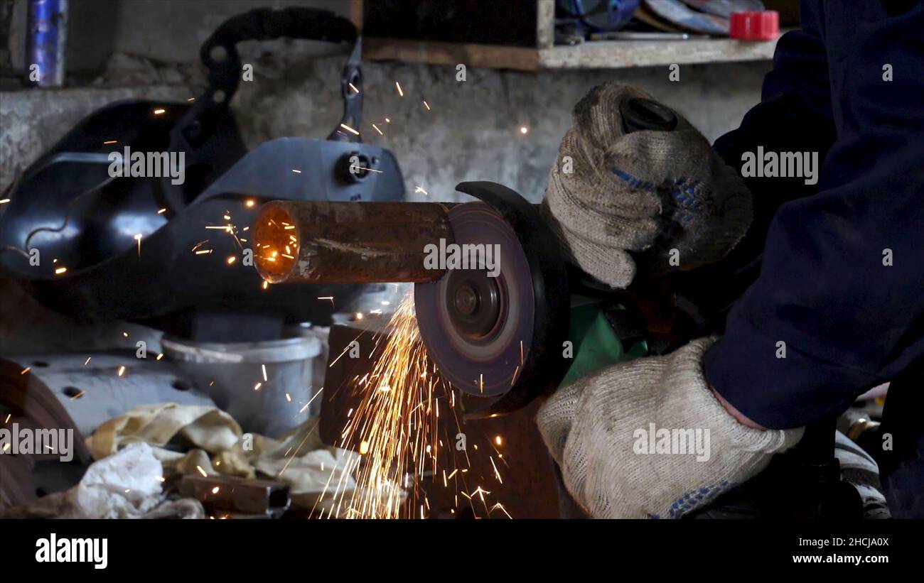 Male hand cuts off pieces of water pipe with angle grinder. Cutting of ...