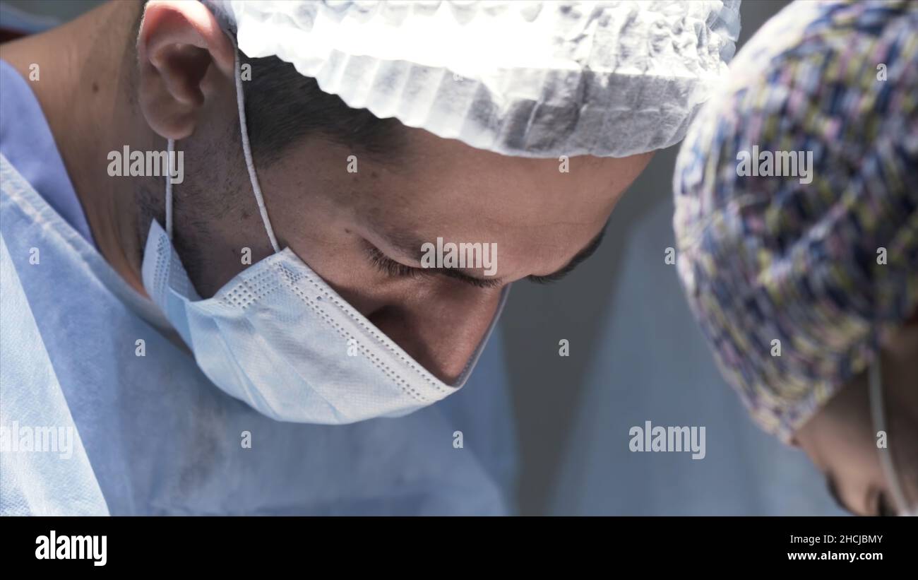 Close up of heads of male surgeons wearing protective masks surgical ...