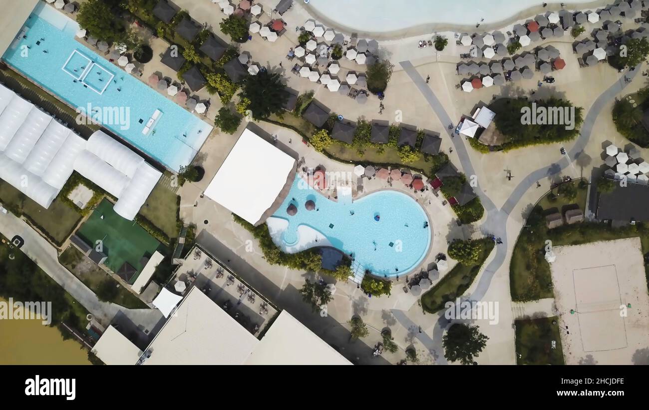 People lying on the sun loungers near the pool, top view. People ...