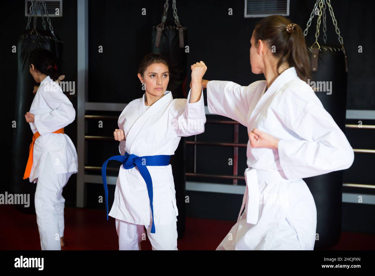 Portrait of woman wearing white kimono sparring with female opponent during martial arts ...