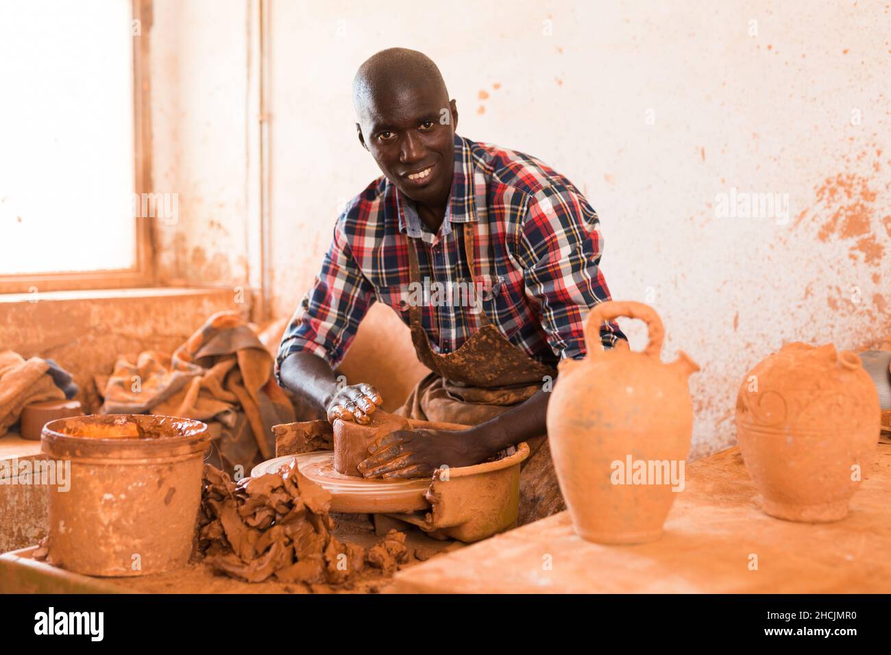 Smiling guy working with clay on potter wheel Stock Photo - Alamy