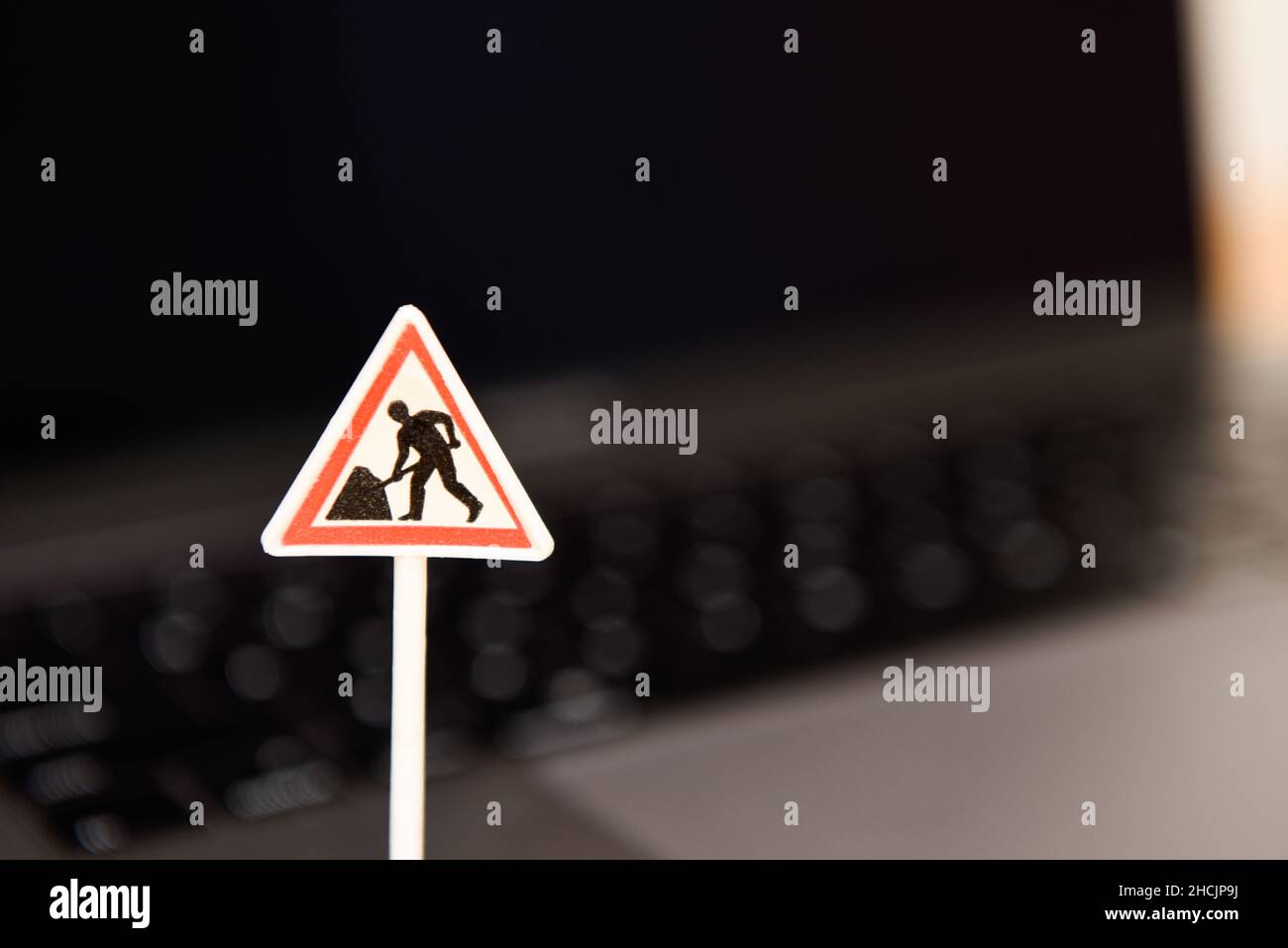 Website under construction sign in front of blank page of computer ...