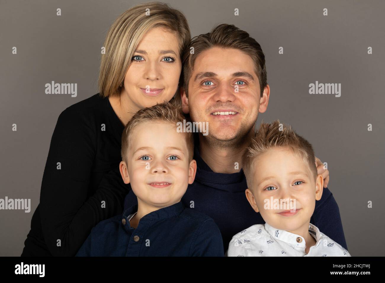 Happy family looking to the camera in front of grey background Stock ...