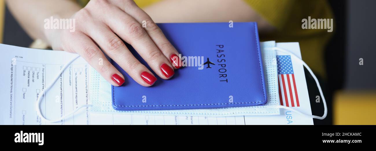 Female hand holding passport with protective medical face mask and ...