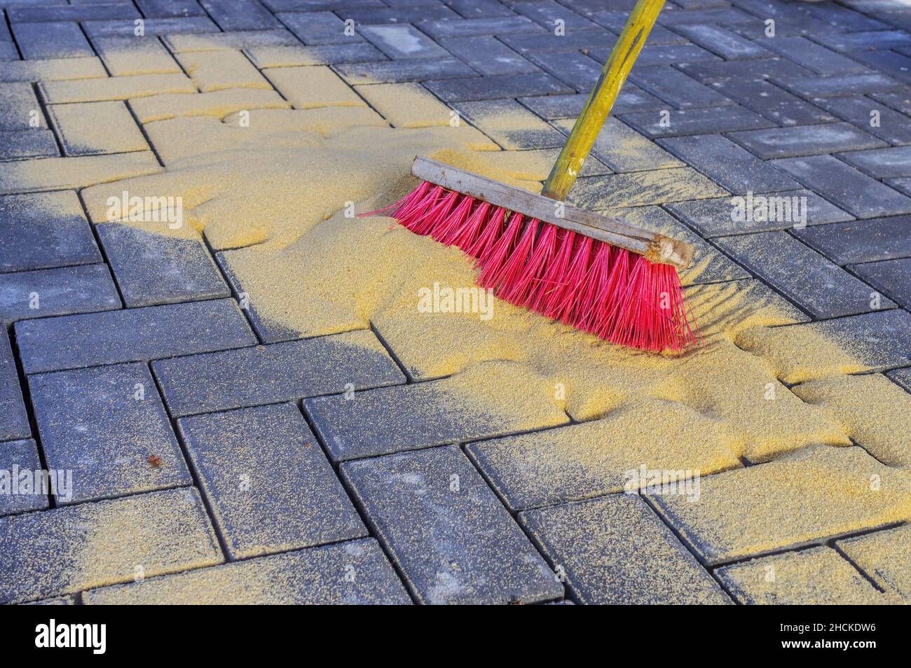 Sweeping in joint sand on a construction site Stock Photo - Alamy