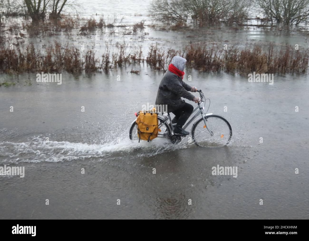 Sutton Gault, UK. 28th Dec, 2021. A person cycles through the flooded ...