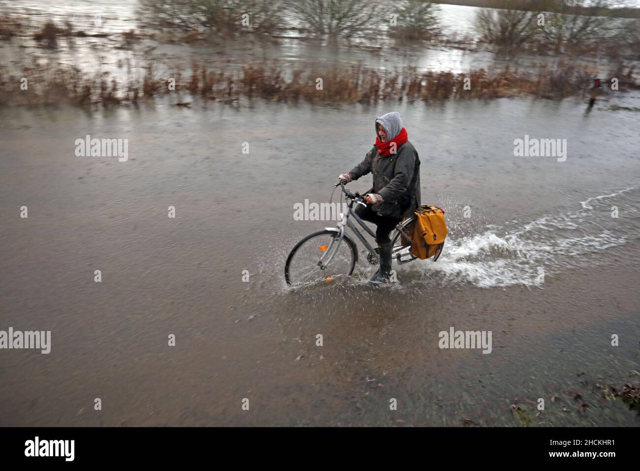 Sutton Gault, UK. 28th Dec, 2021. A person cycles through the flooded ...