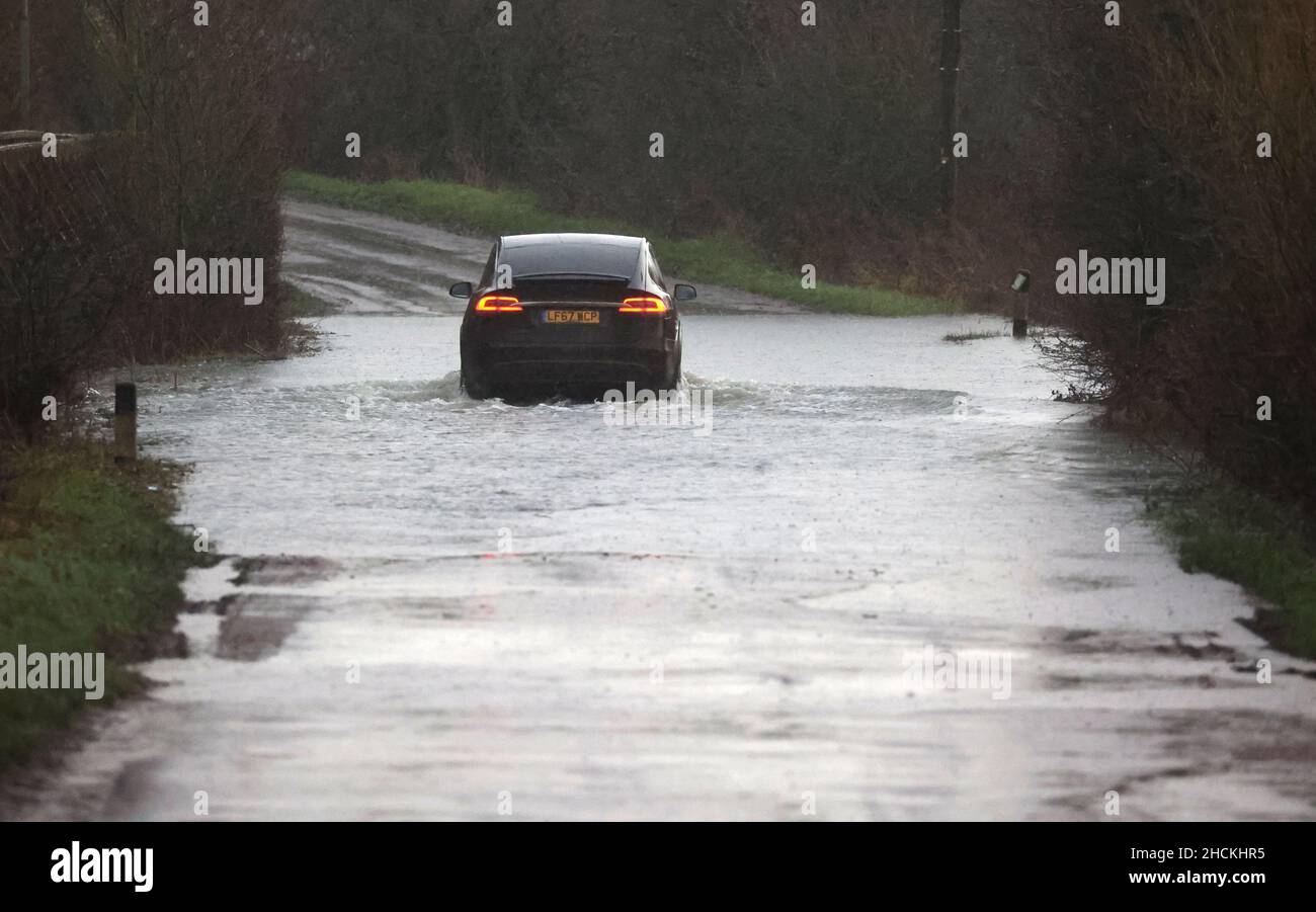 Sutton Gault, UK. 28th Dec, 2021. A vehicle gets through the flooded ...