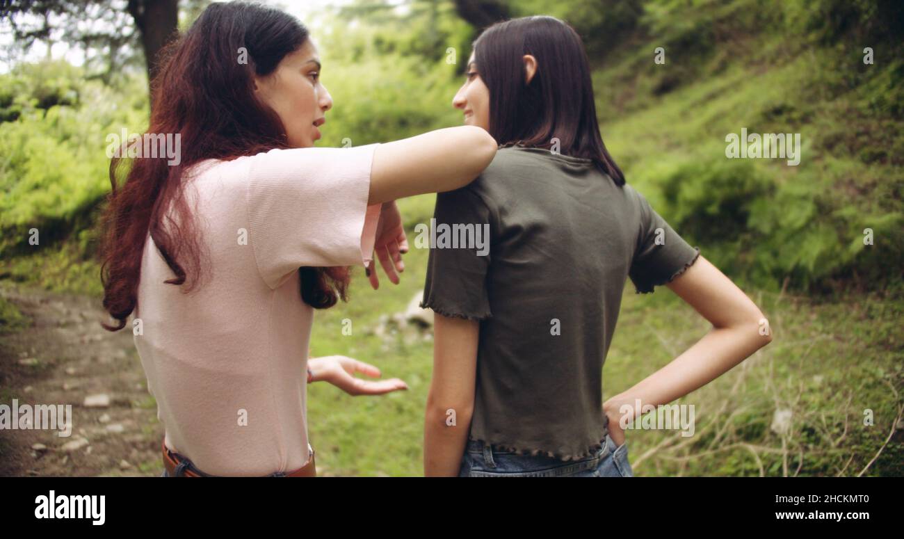 Back view of two young beautiful Indian girls standing and talking in ...
