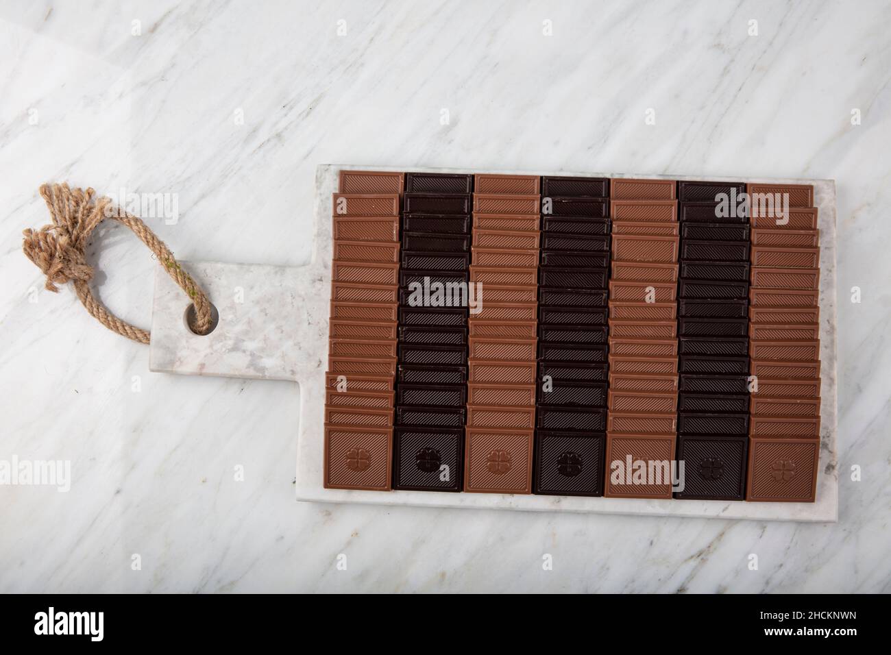 Bitter square madlen chocolates on marble background. Milky and bitter ...