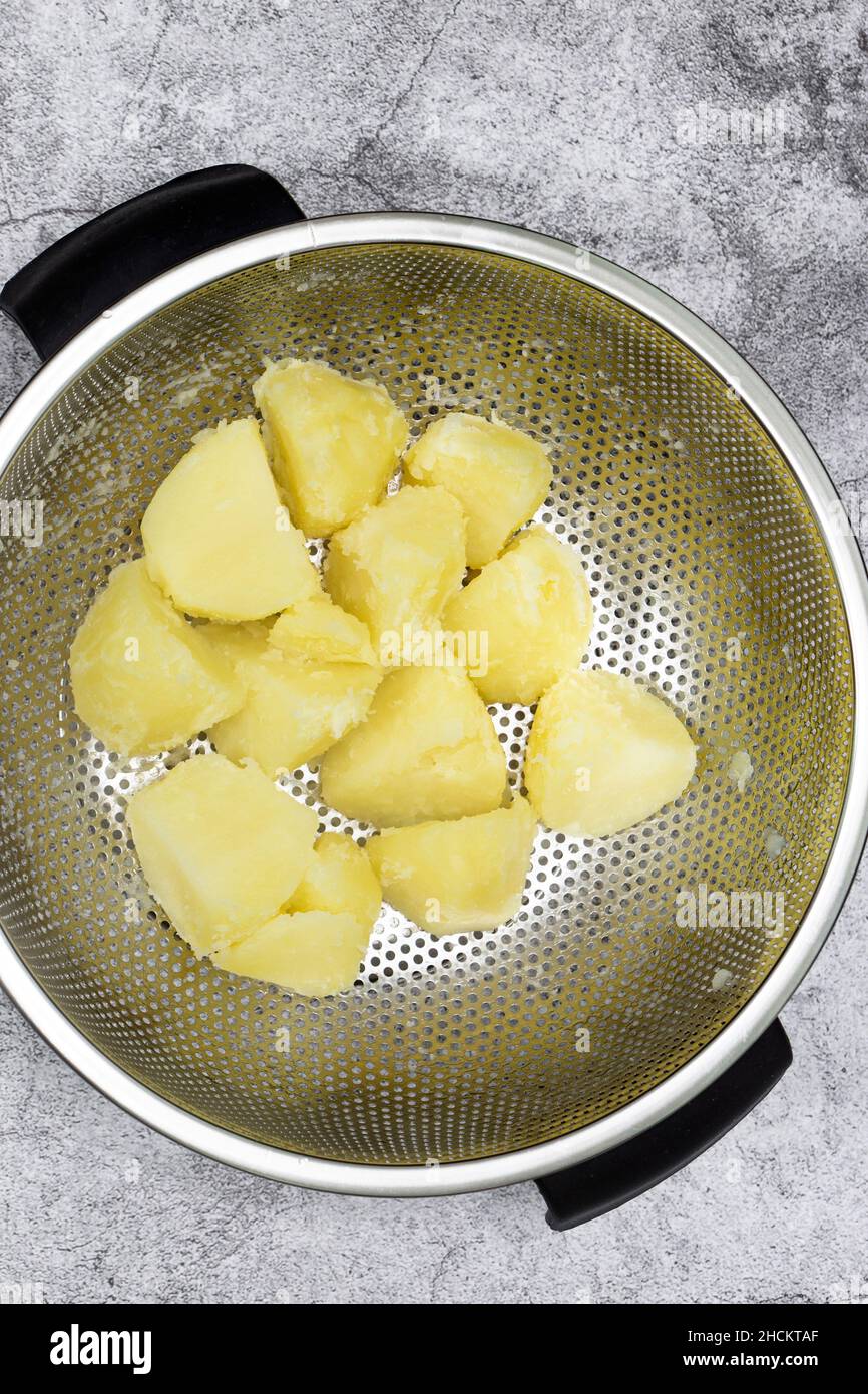 Part boiled potato in a metal colander strainer, ready to be roasted in ...