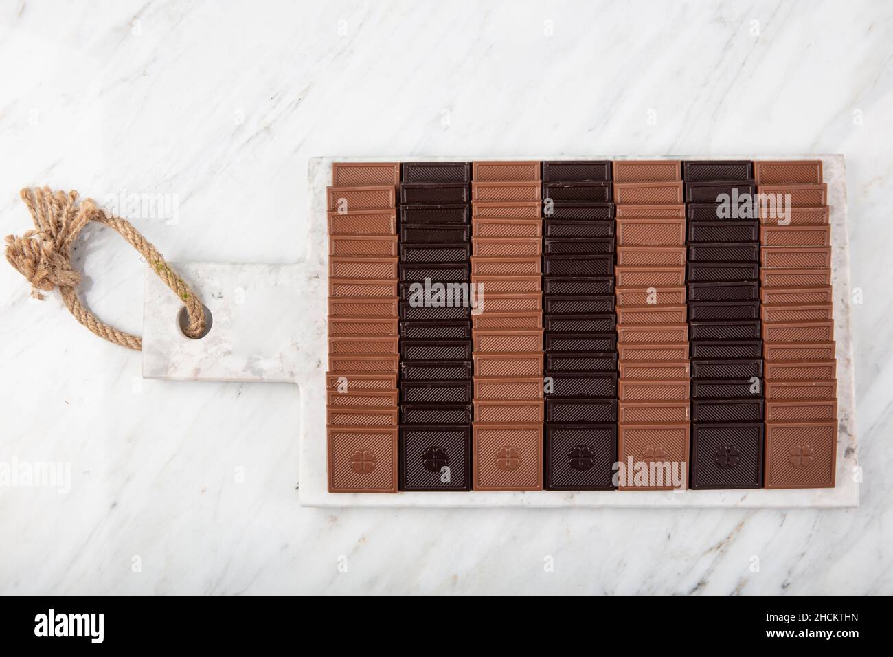 Bitter square madlen chocolates on marble background. Milky and bitter ...