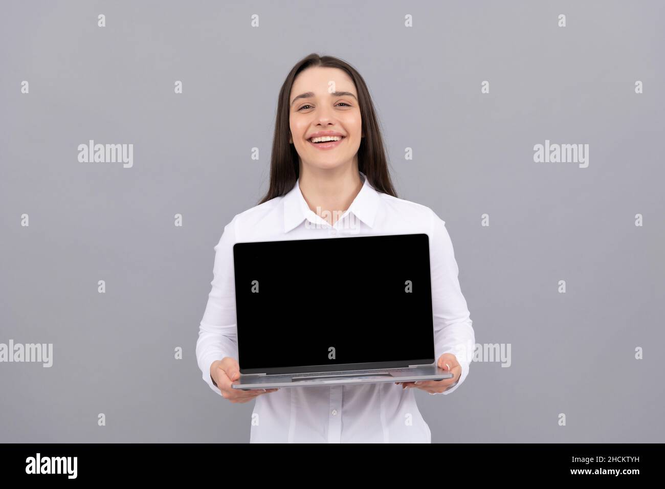 happy woman in white shirt showing computer ad presentation, copy space ...