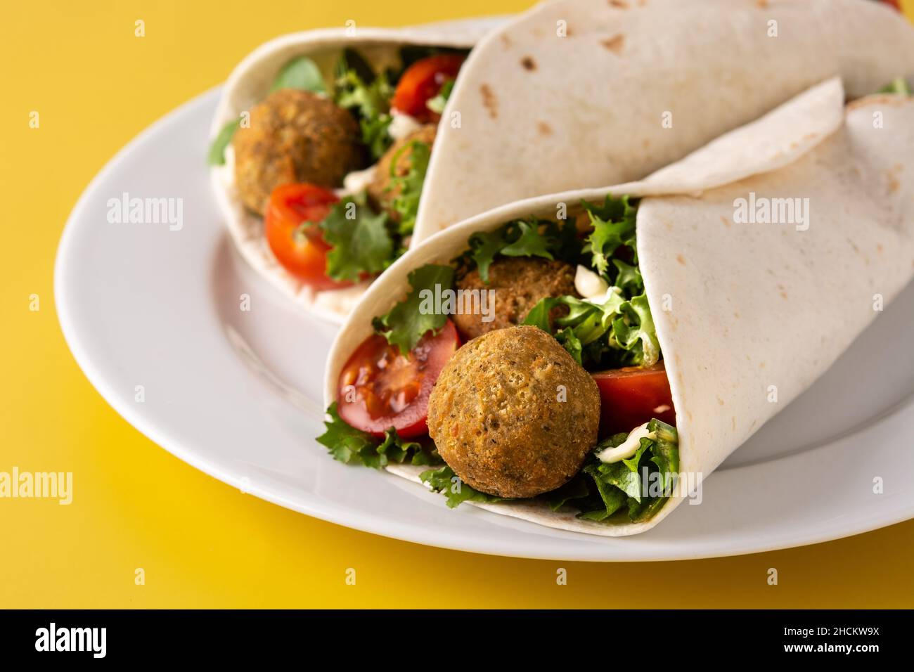 Tortilla wrap with falafel and vegetables on yellow background Stock ...