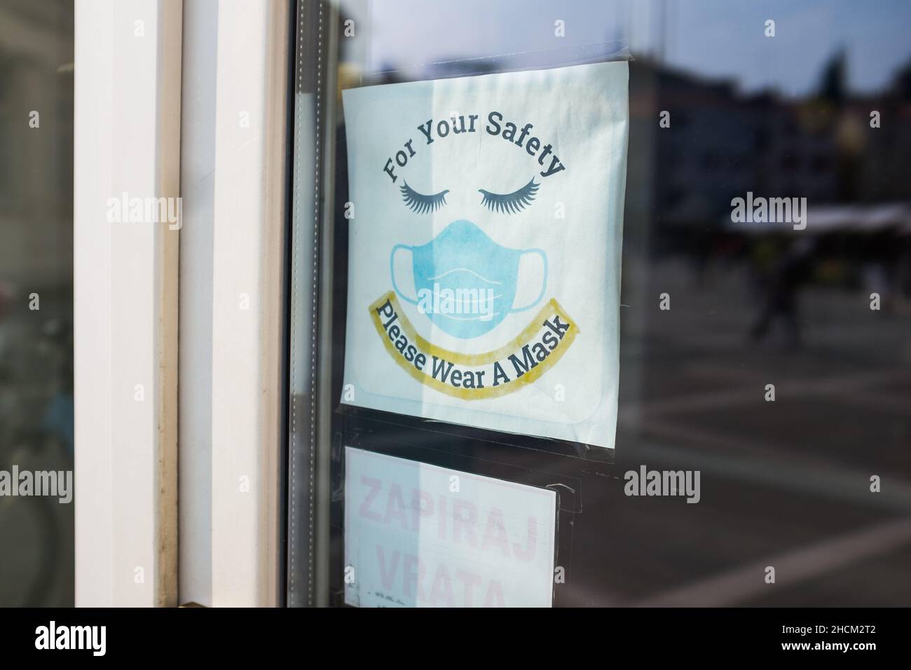 Paper sign board on shop entrance door "FOR YOUR SAFETY PLEASE WEAR A ...