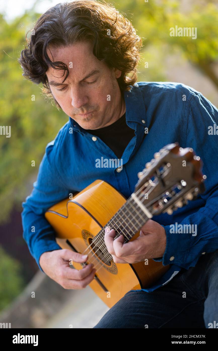 Middle-aged man playing Spanish guitar sitting on park bench Stock ...