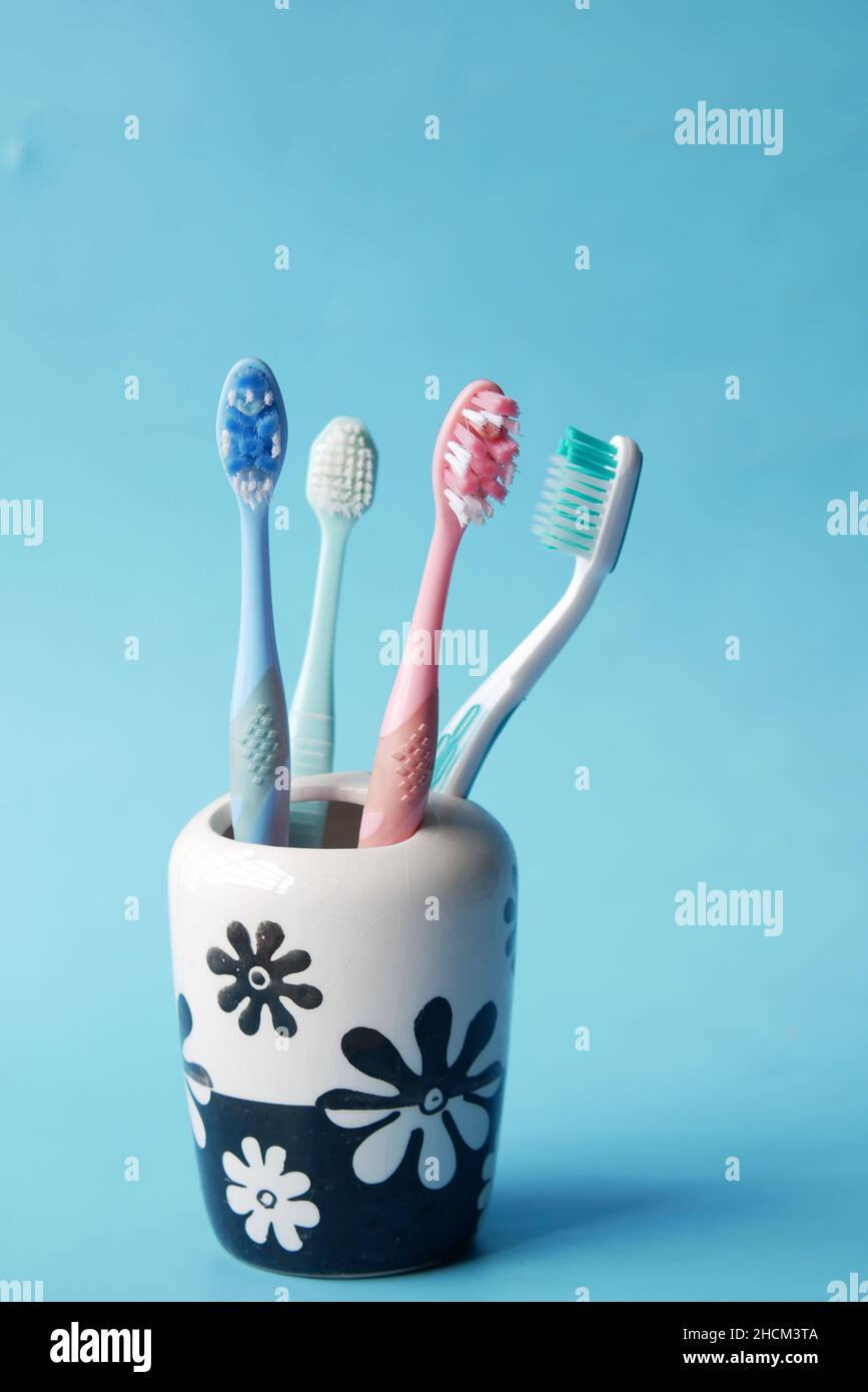colorful toothbrushes in white mug against blue background Stock Photo ...