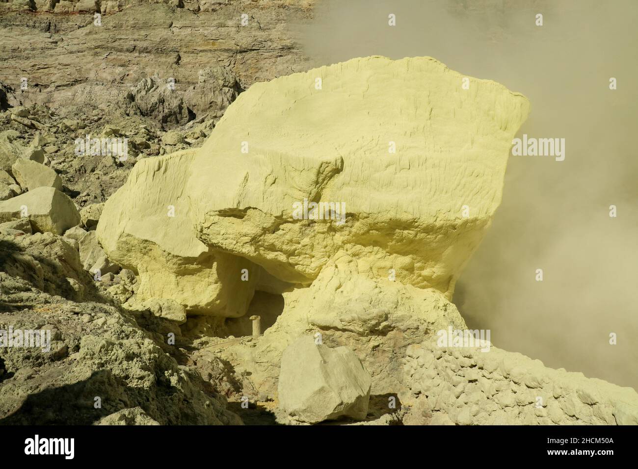Lava rock covered in monoclinic sulphur crystals on a black reflective ...