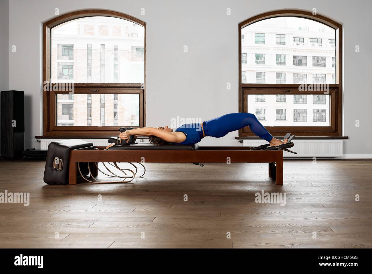 The instructor does exercises on the reformer, a beautiful girl trains ...