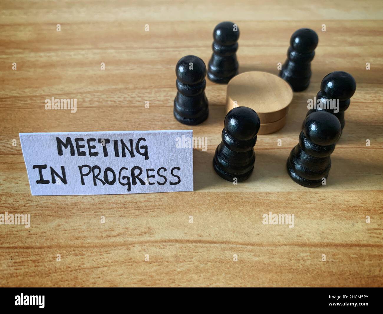 Meeting in progress text on a paper note with chess pawn circling a ...