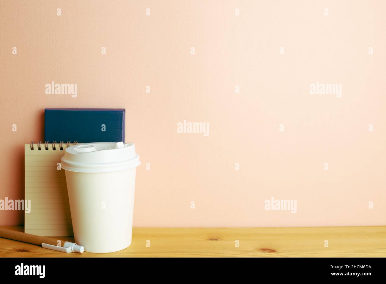 Notebook, pen, paper coffee cup on wooden desk. pink wall background ...