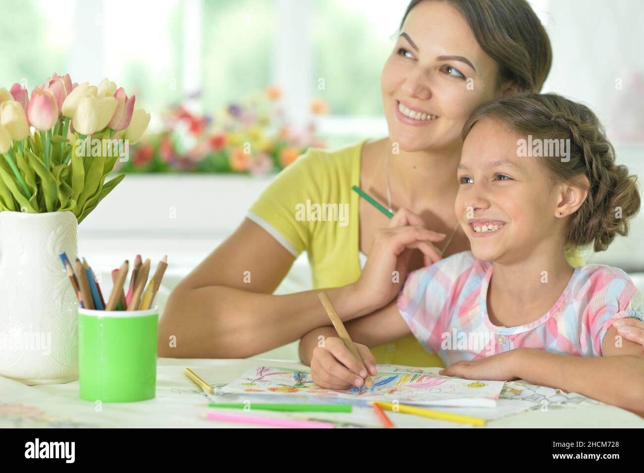 Cute girl with mother drawing at the table at home Stock Photo - Alamy