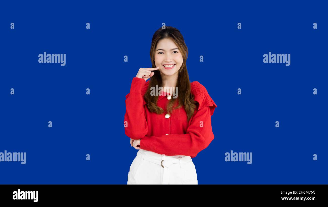 Portrait of an Asian female pointing to her cheek with her finger with ...